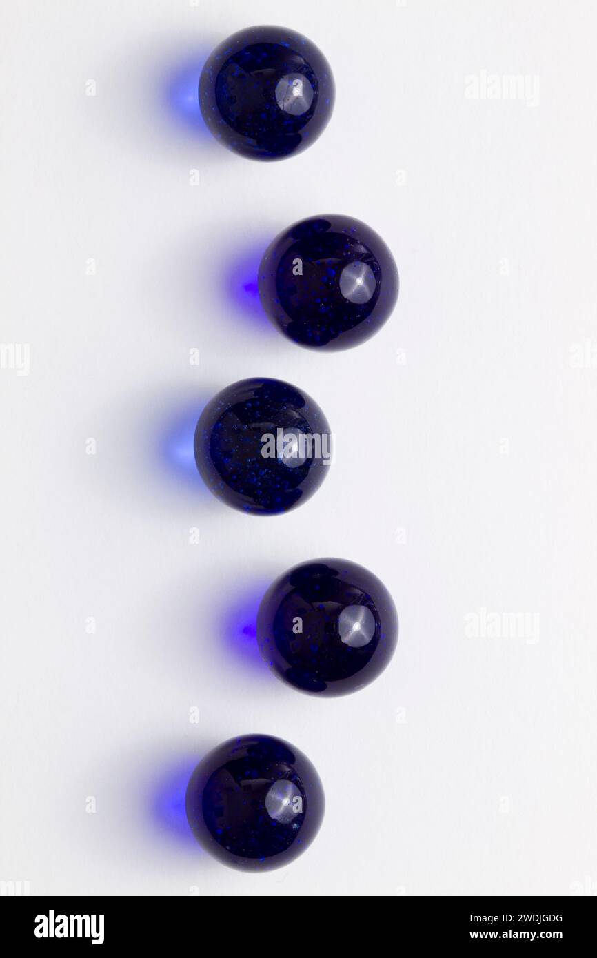 Blue marbles staggered in a row Stock Photo - Alamy