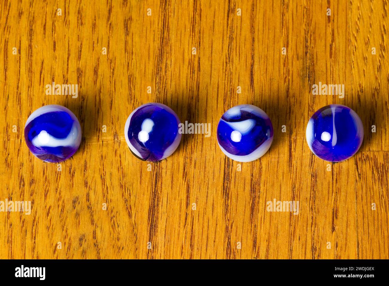 A row of blue and white swirl marbles on a game board Stock Photo - Alamy