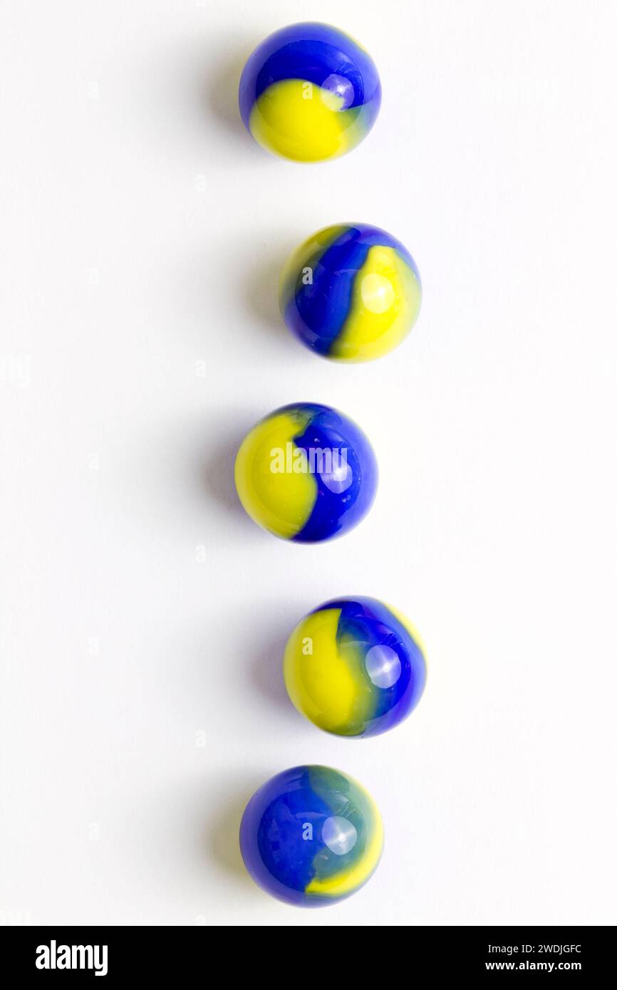 Blue and yellow marbles staggered in a row Stock Photo - Alamy