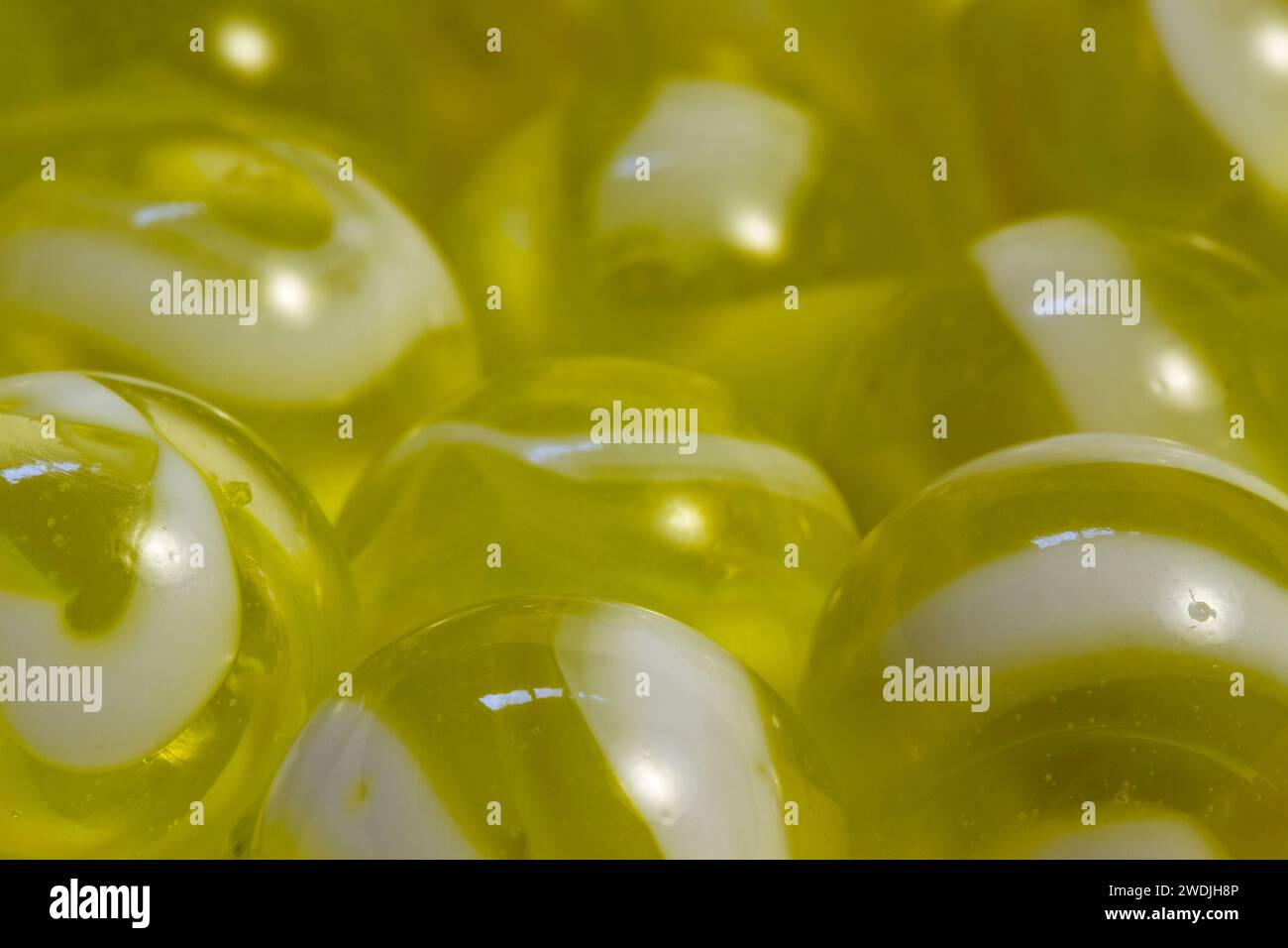 A collection of yellow and white swirl glass marbles Stock Photo - Alamy
