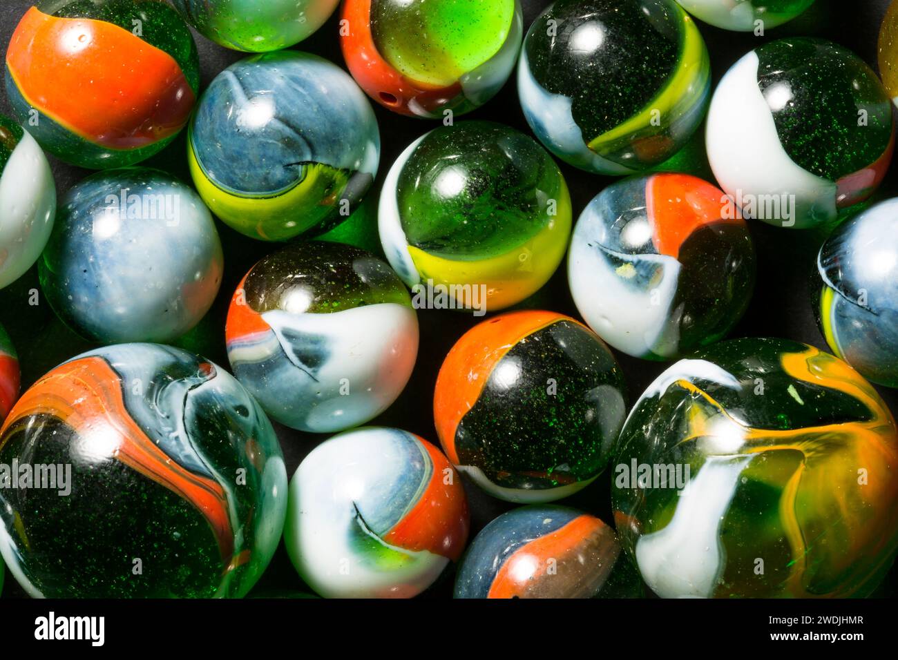 Green, orange, yellow, and white swirl glass marbles Stock Photo - Alamy