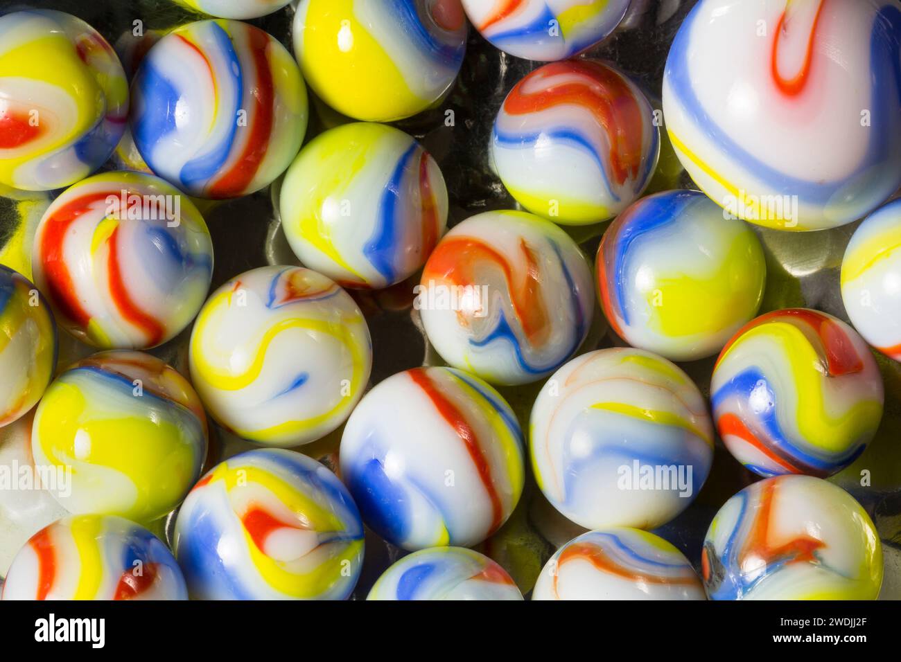 A collection of white, blue, orange, and yellow swirl glass marbles ...