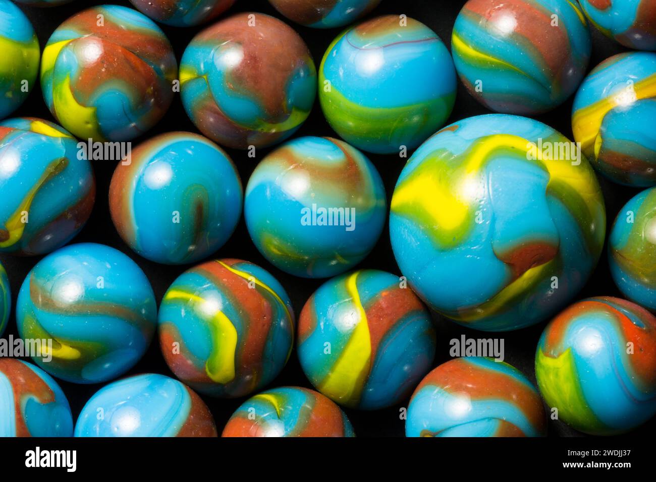 Blue, yellow, and orange swirl glass marbles Stock Photo - Alamy