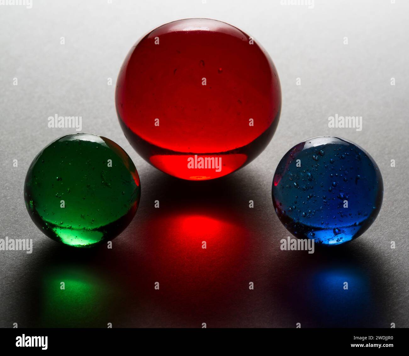 Three glass marbles - a red, a blue, and a green Stock Photo - Alamy