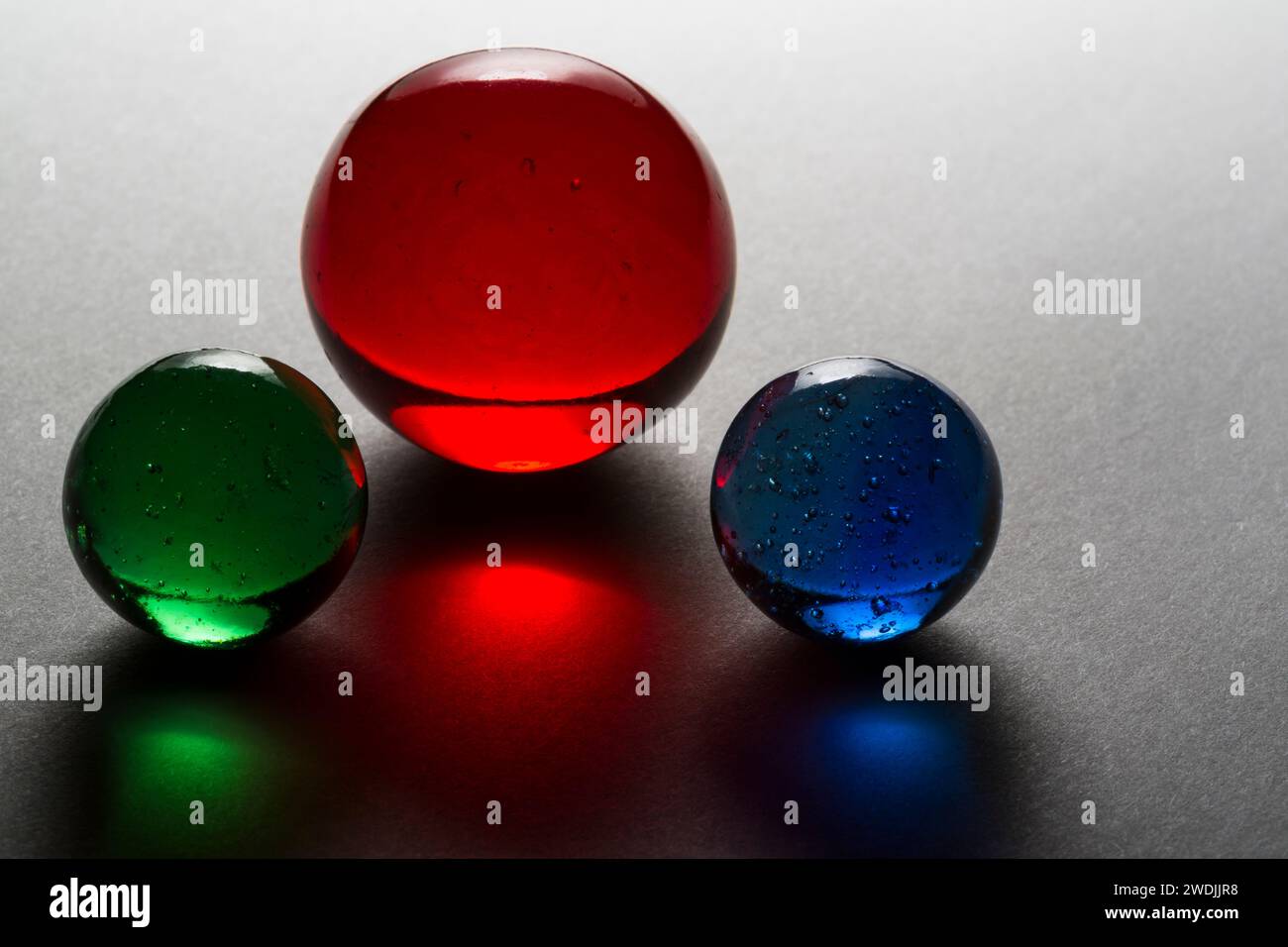 Three glass marbles - a red, a blue, and a green Stock Photo - Alamy