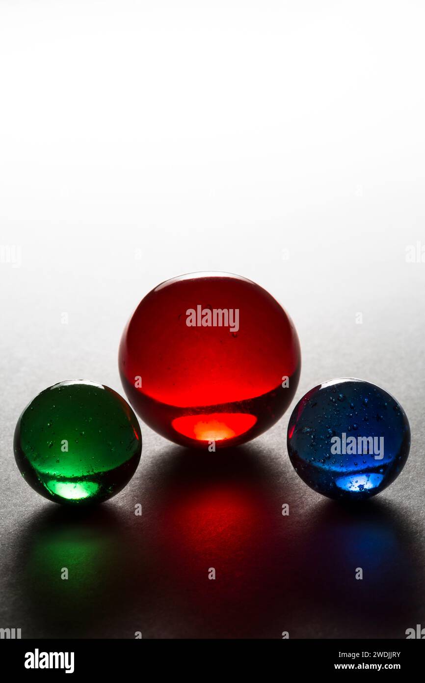 Three glass marbles - a red, a blue, and a green Stock Photo - Alamy