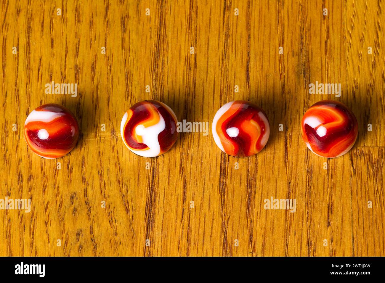 Red, orange, and white swirl glass marbles on a wooden game board Stock ...