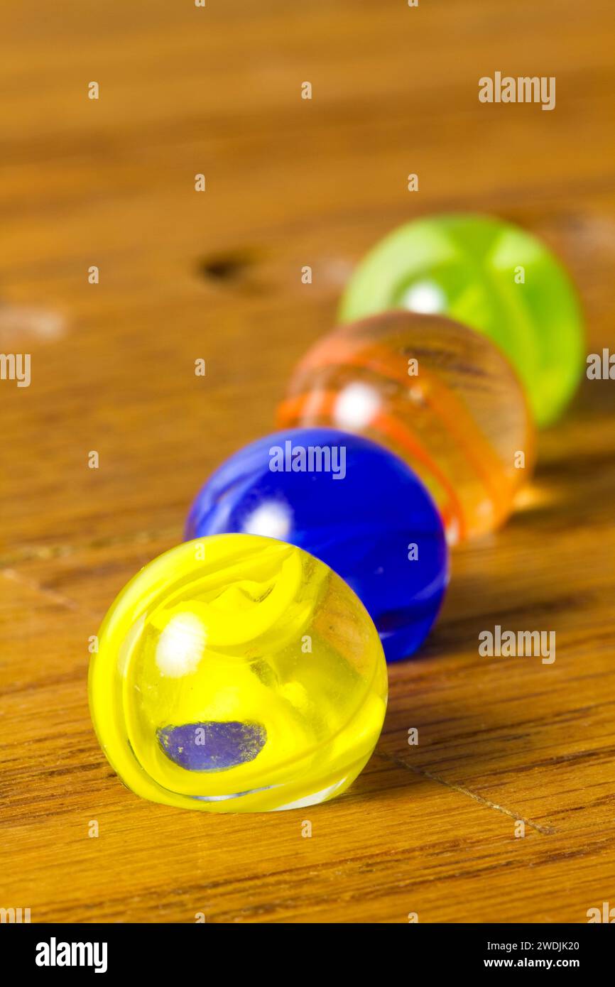 Four swirl glass marbles on a wooden game board Stock Photo - Alamy