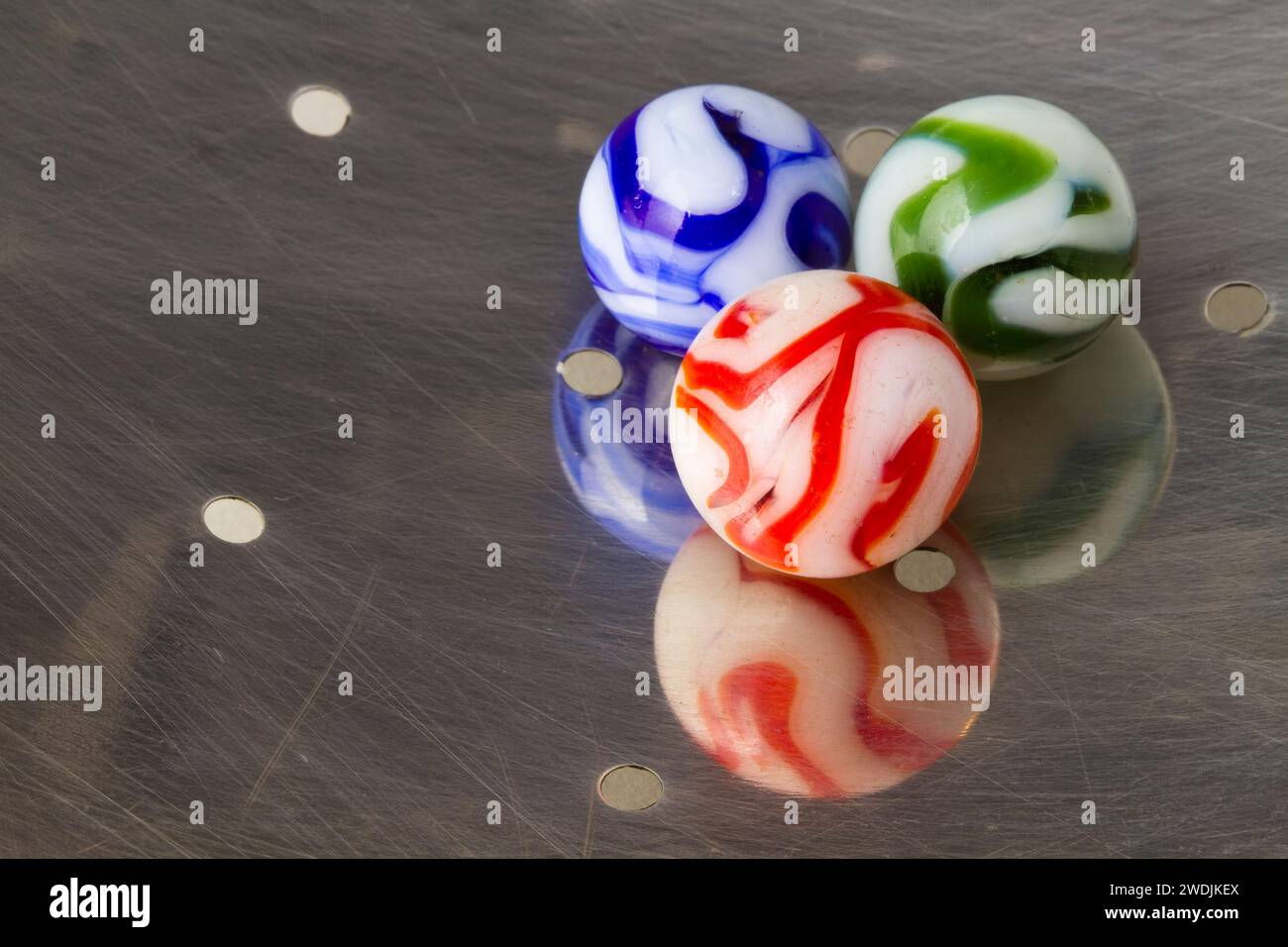 Colorful swirl glass marbles in a metal strainer Stock Photo - Alamy
