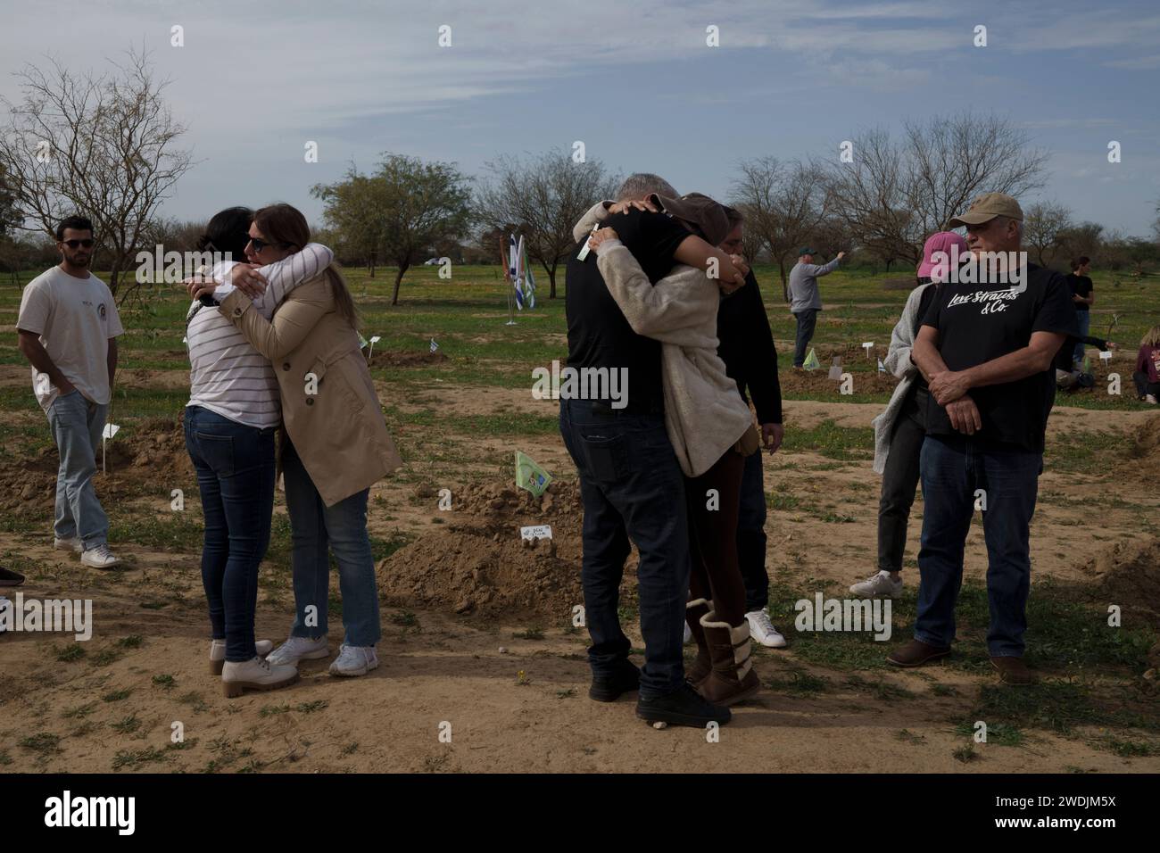Friends and relatives embrace as they plant a tree in memory of the ...