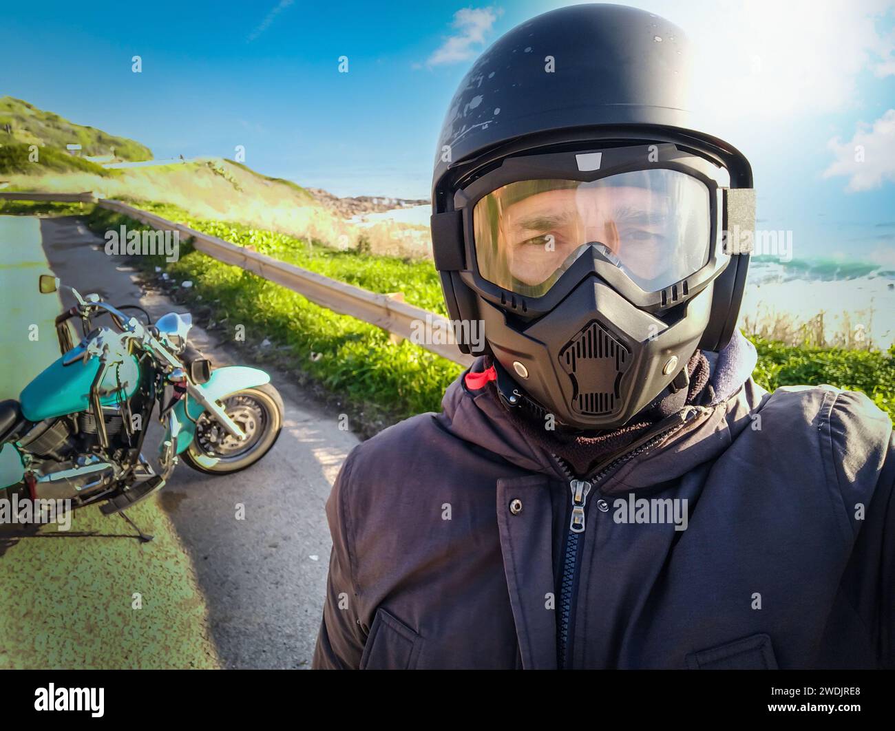 Selfie of a biker with helmet by the sea with a classic motorcycle ...