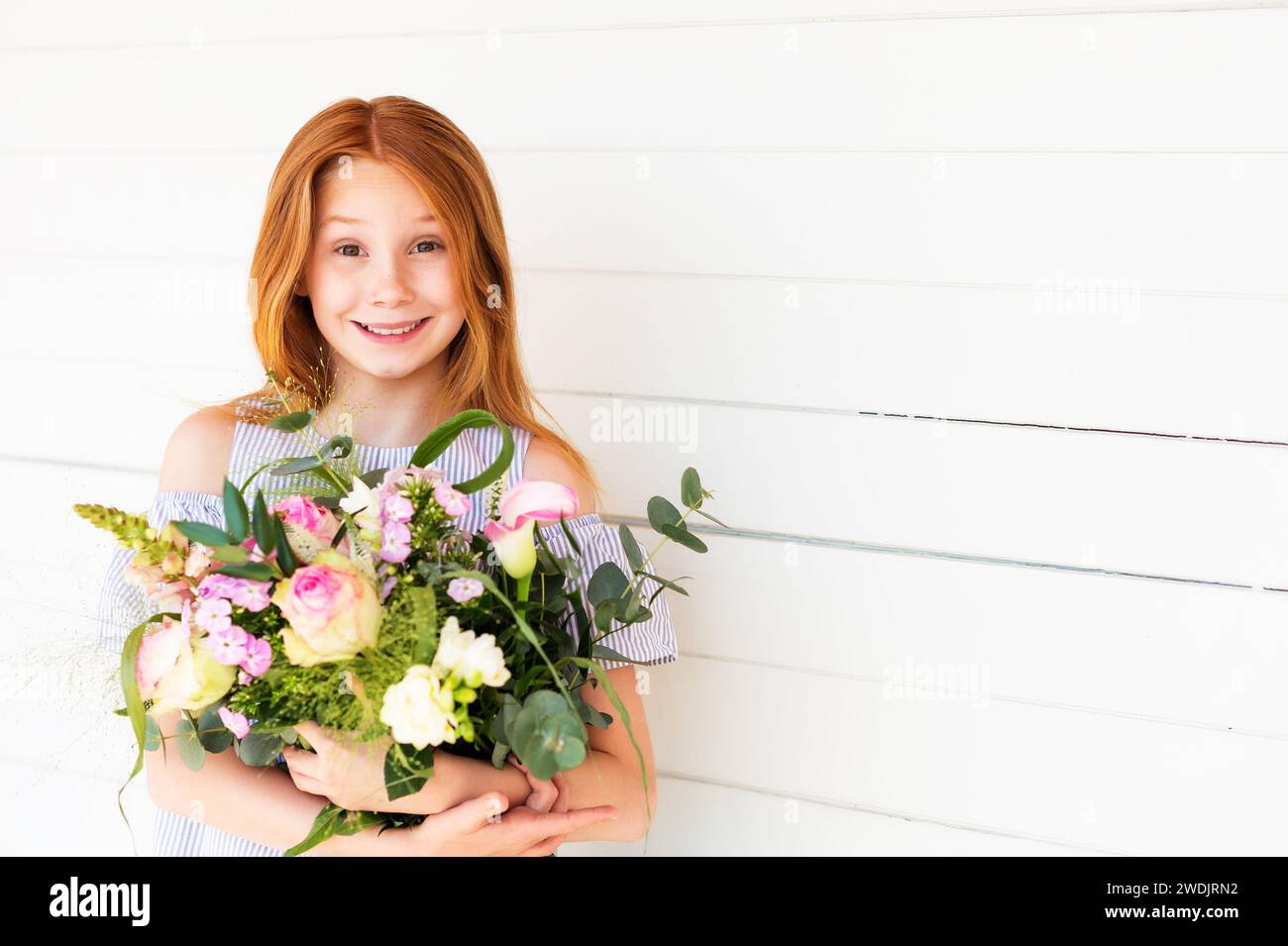 Close up portrait of adorable red hair kid girl holding big flower ...