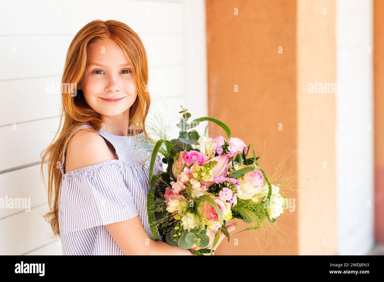 Close up portrait of adorable red hair kid girl holding big flower ...