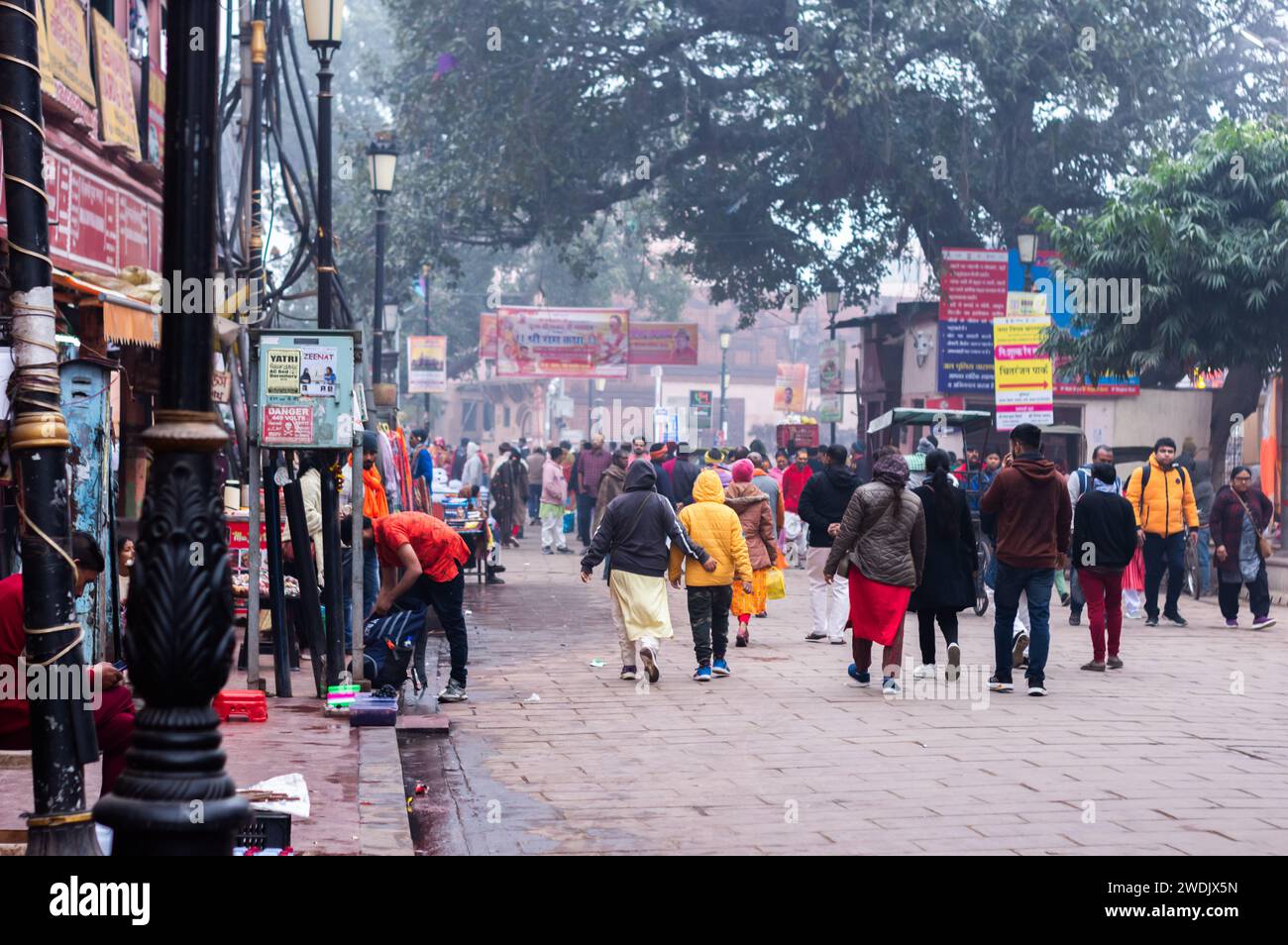 People walking in the city street of Varanasi in a winter foggy morning ...