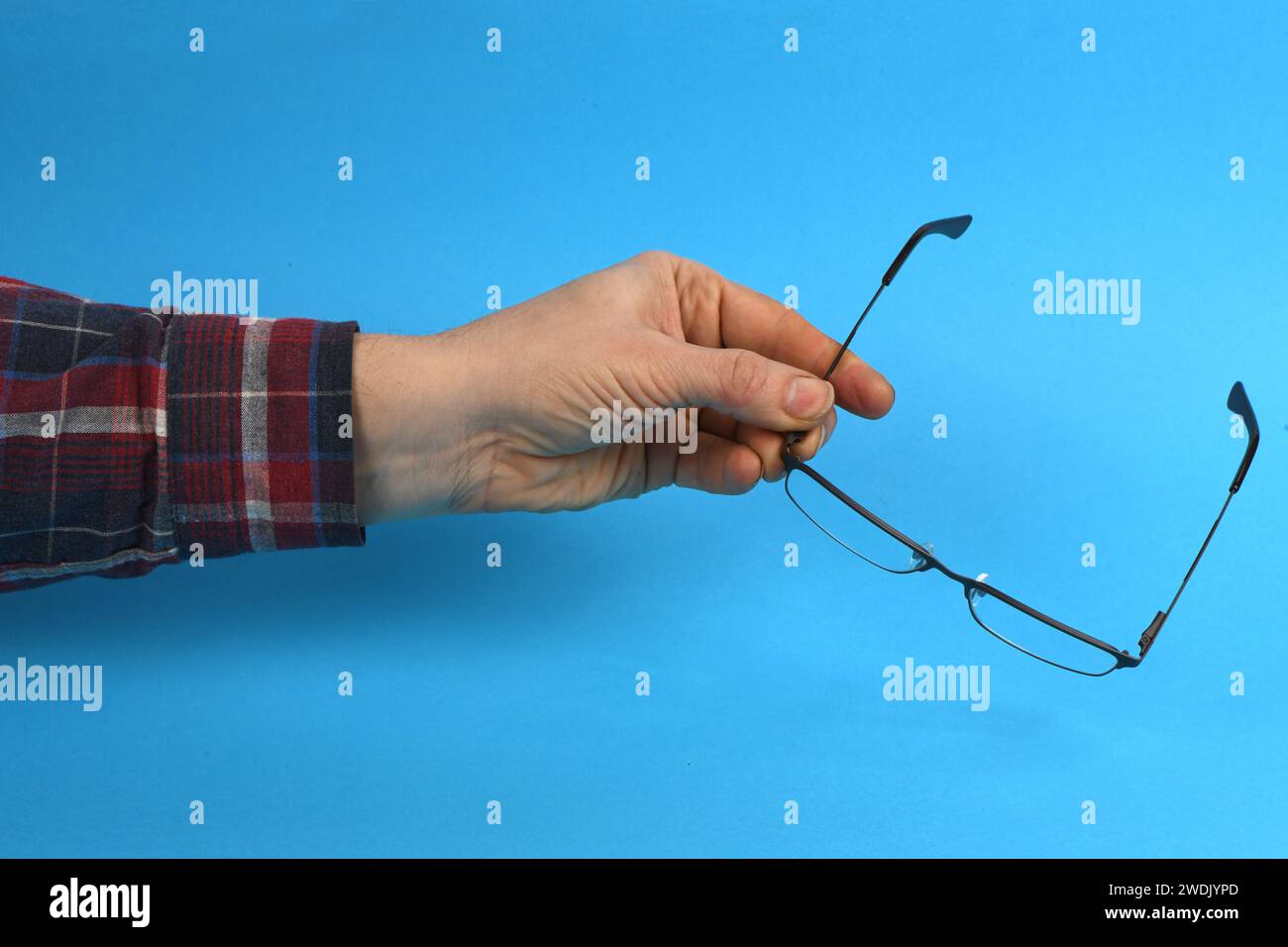 Hand holding plastic black glasses, isolated on blue background. High ...