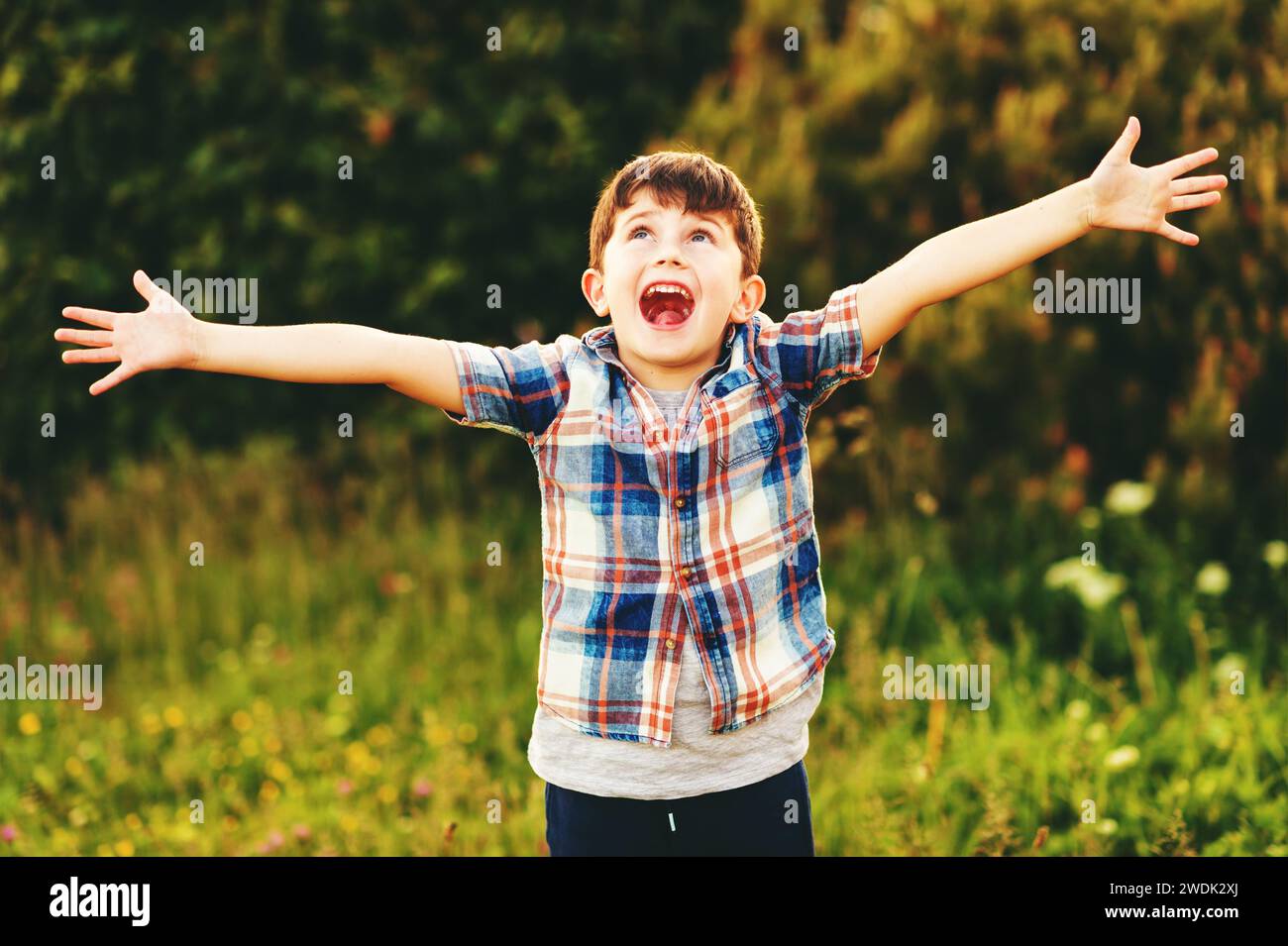 Happy kid boy of 6 year old having fun outdoors wearing blue plaid ...