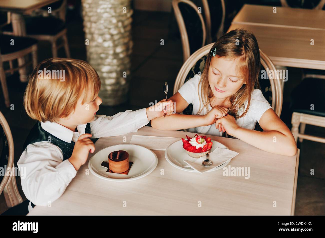 Little kids enjoying delicious desserts in a cafe Stock Photo - Alamy