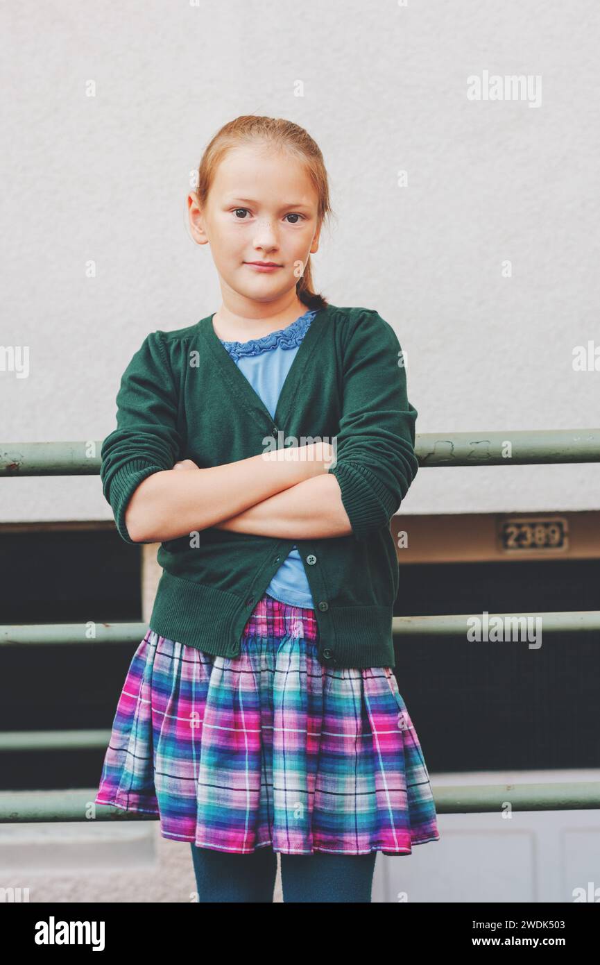 Outdoor portrait of pretty little 7-8 year old schoolgirl wearing ...