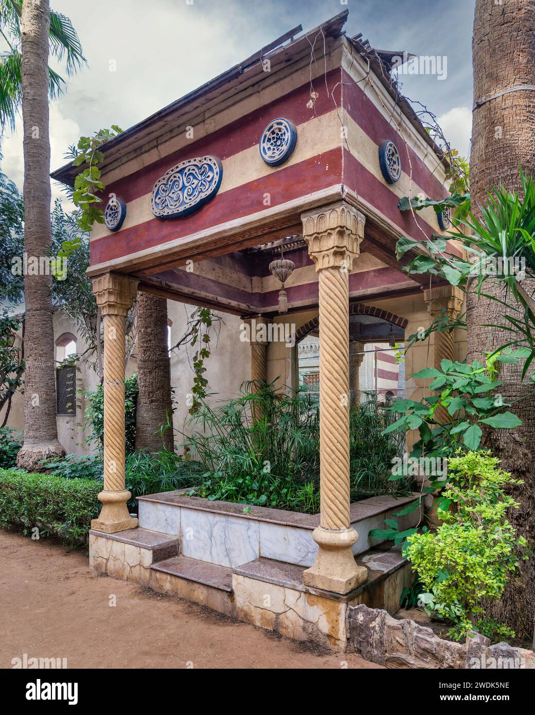 Charming stone gazebo with carved columns nestled amidst lush greenery in a serene urban garden ...