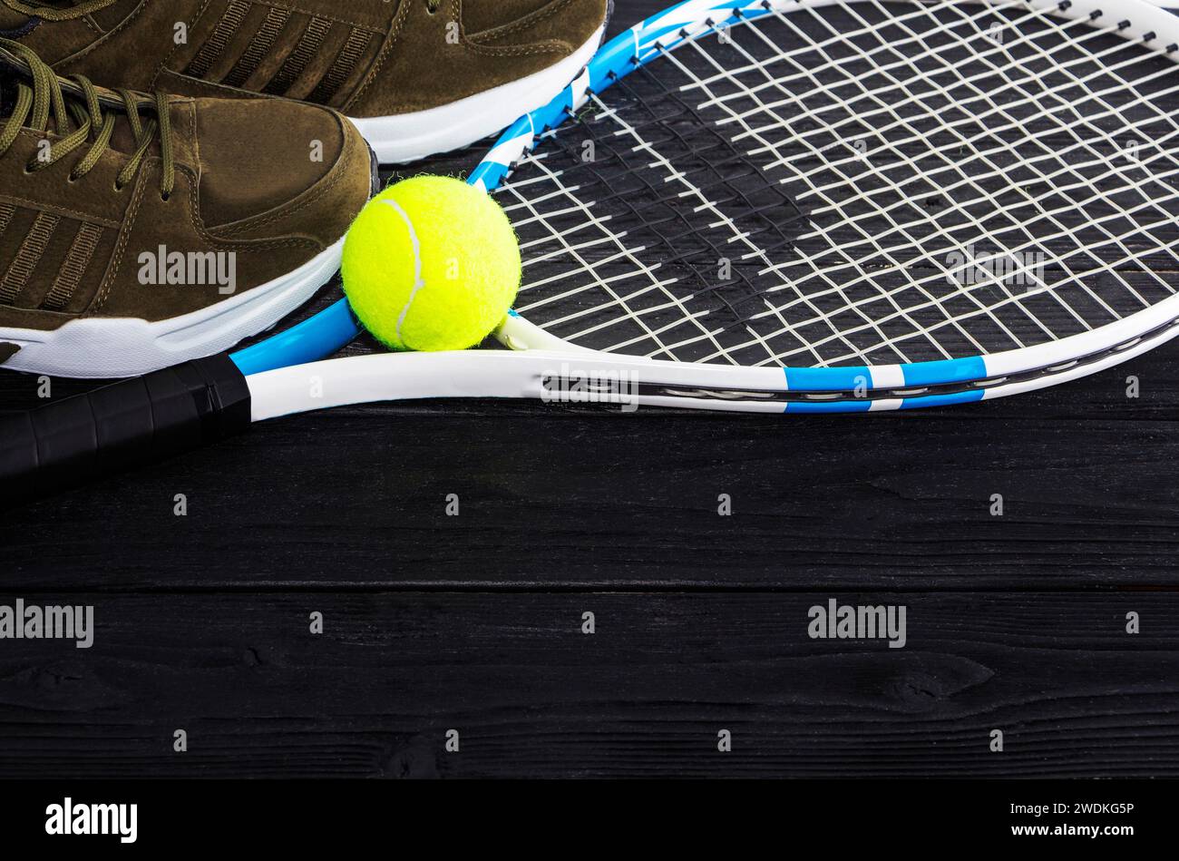 Tennis on a black wooden background. running shoes, tennis racket, ball ...