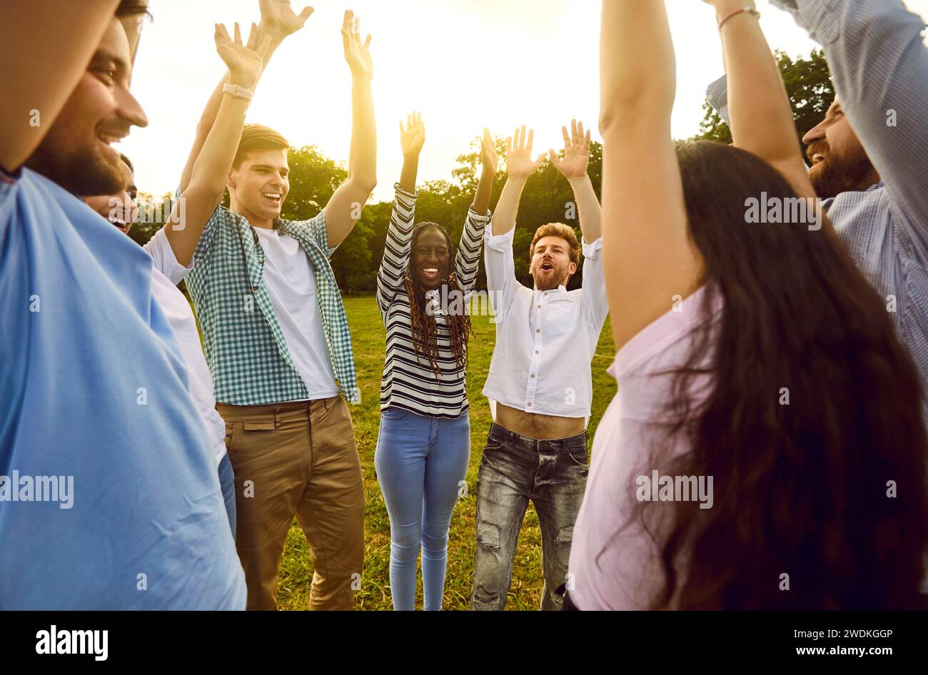 Happy students friends standing together outdoor in summer park raising ...