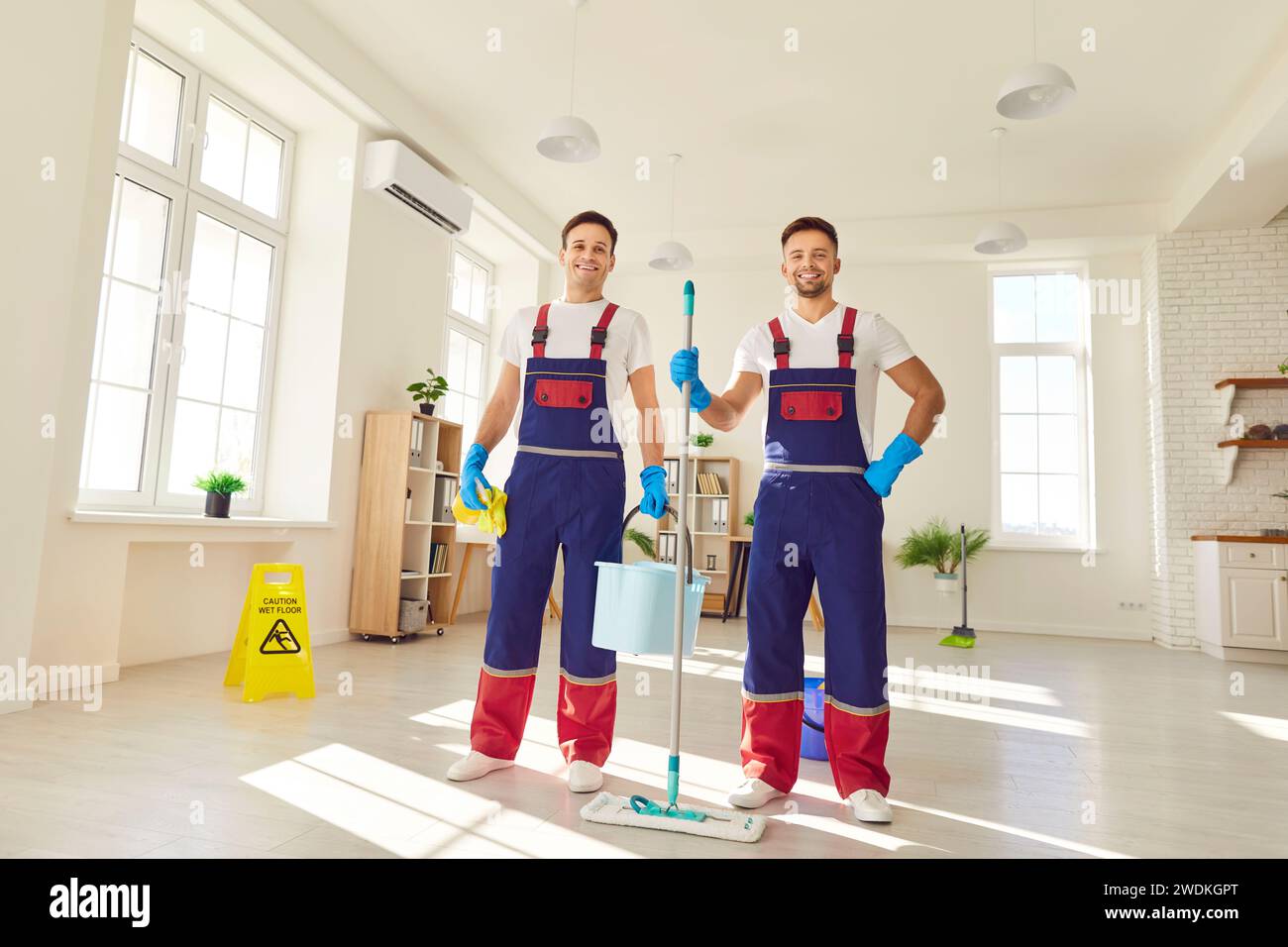 Two happy men from janitor service standing with mop and water bucket ...