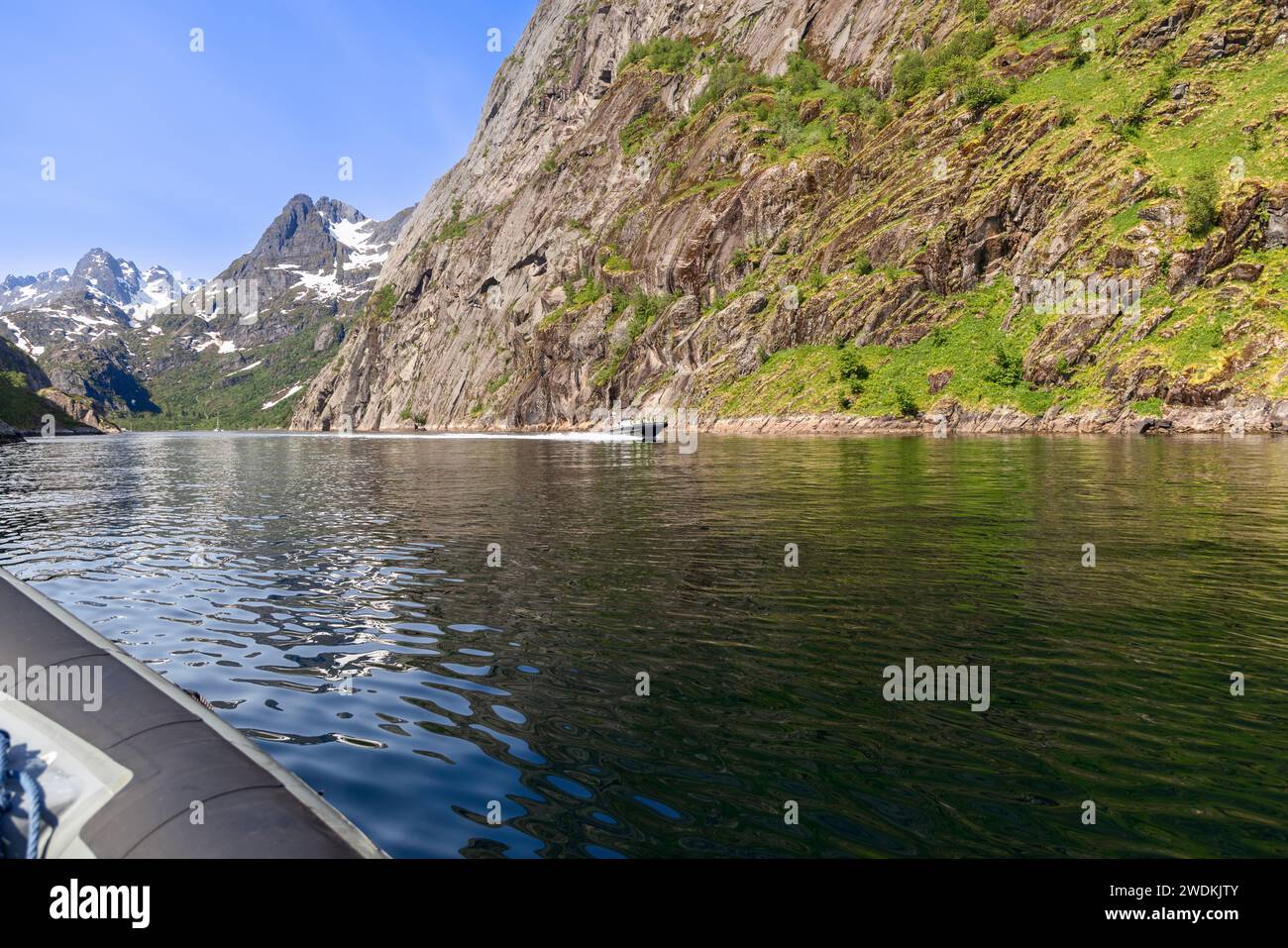 In the heart of the Lofoten fjords, a speed boat tours the rugged ...