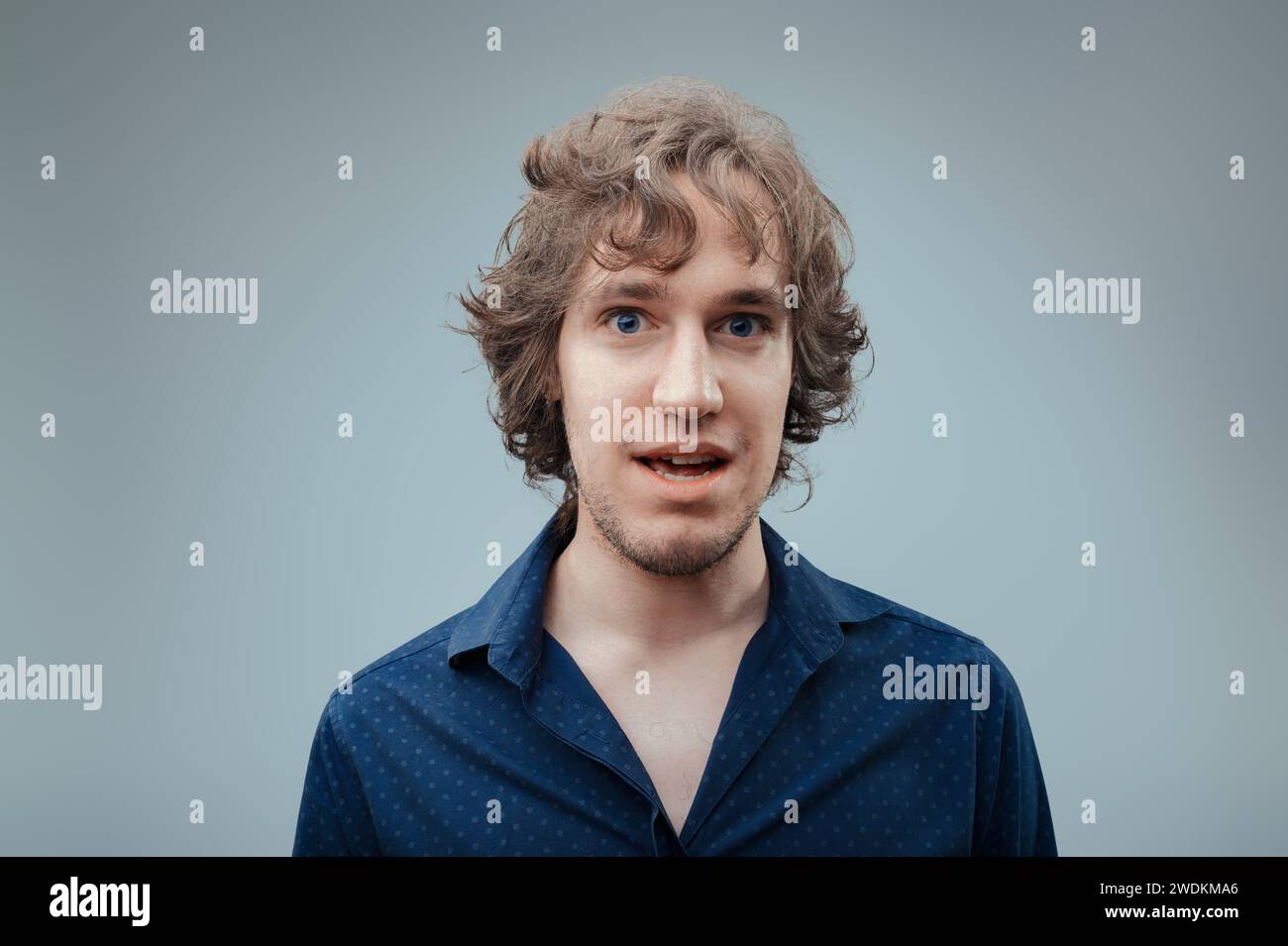 Young man with an intrigued expression and tousled hair wears a navy ...