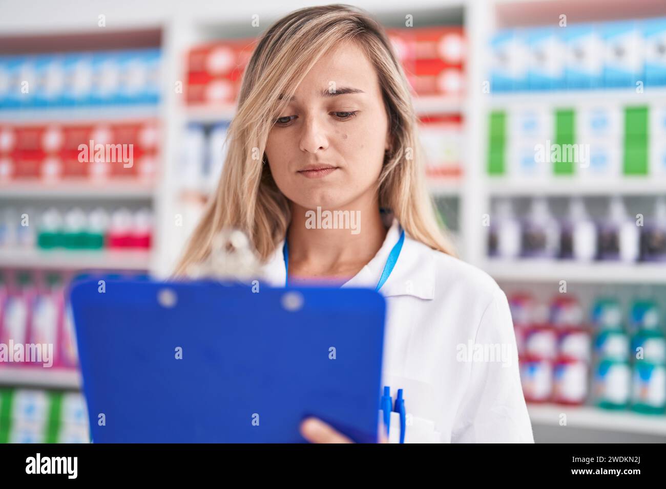 Young blonde woman pharmacist reading document at pharmacy Stock Photo ...