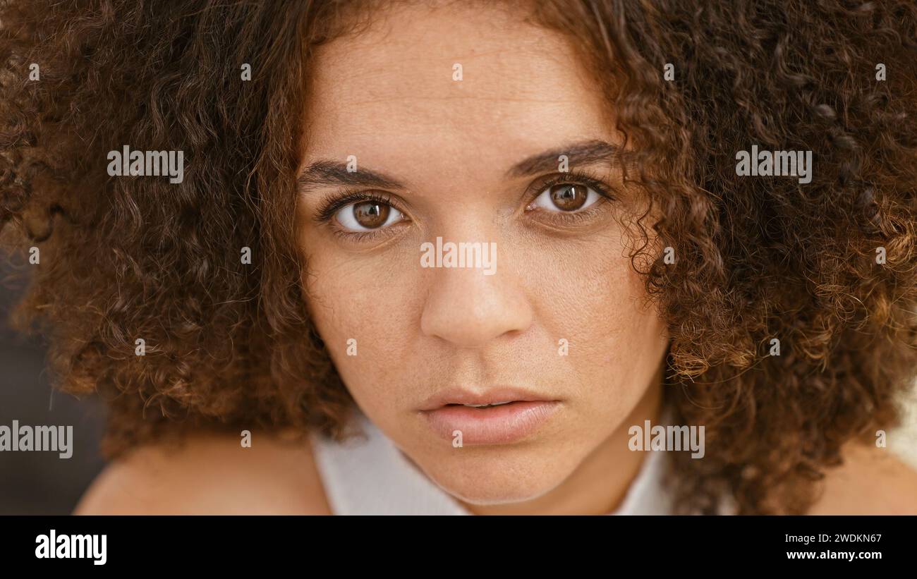 A beautiful young hispanic woman with curly hair poses indoors ...