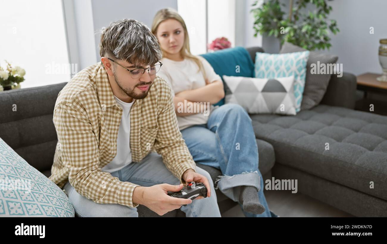 A woman looks on displeased as her partner focusedly plays video games ...