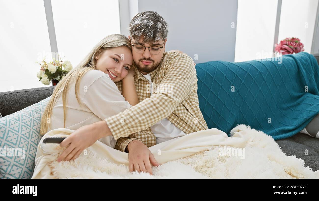 A loving couple cuddles on a couch in a cozy living room, displaying ...