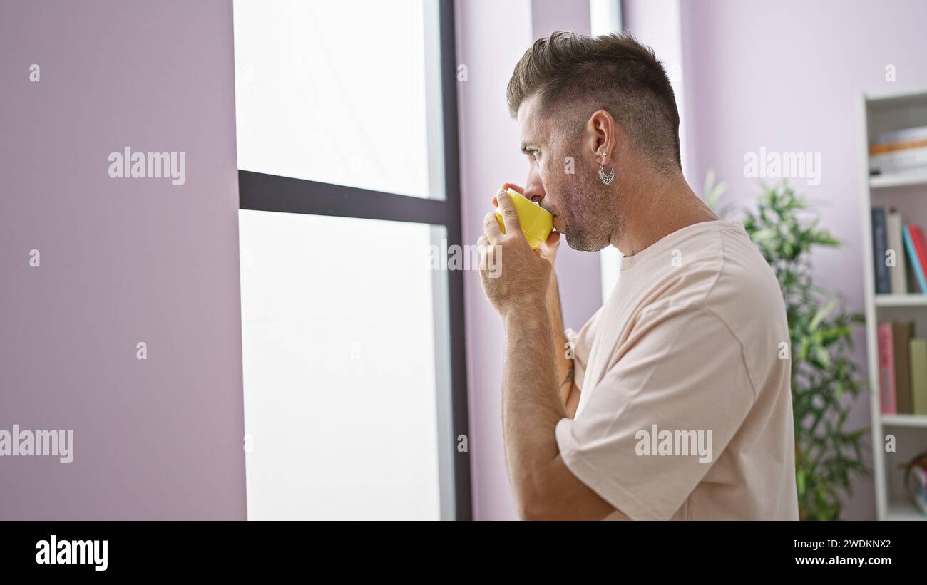 Troubled young hispanic man at home, drinking his morning coffee ...