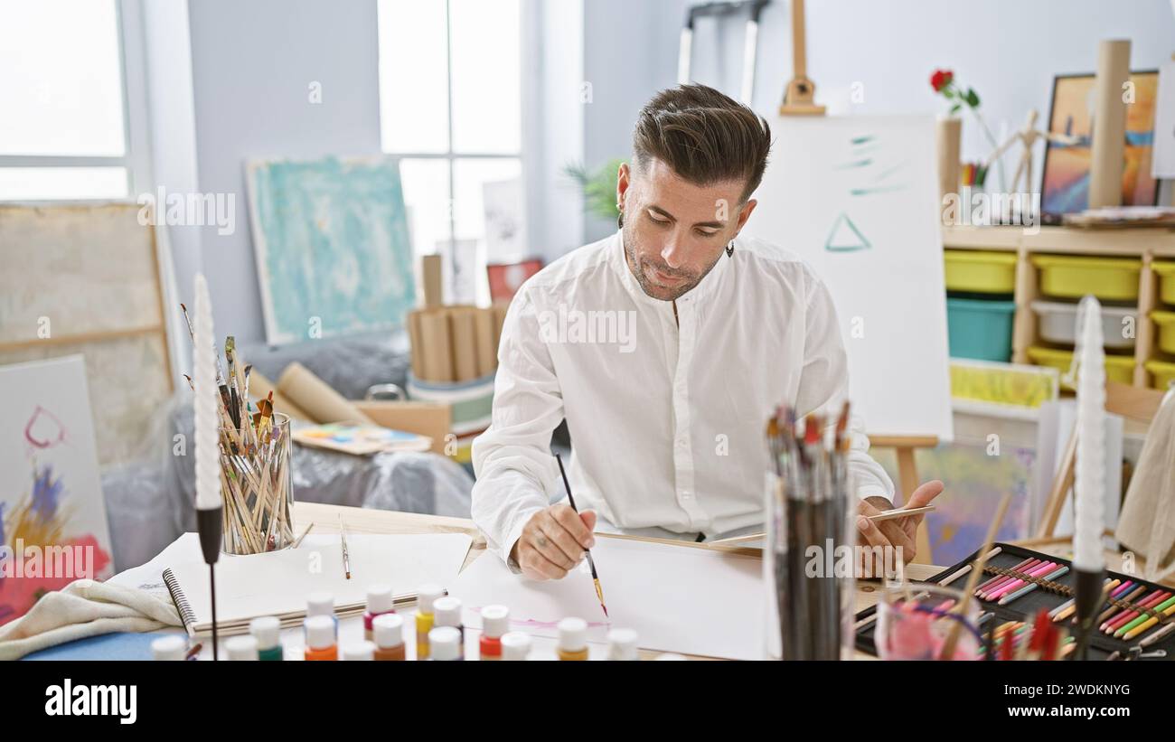 Young, handsome hispanic man ardently drawing on paper, deeply ...