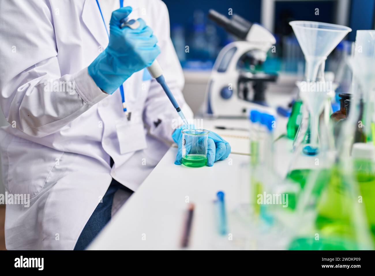 Young bald man scientist pouring liquid on test tube at laboratory ...