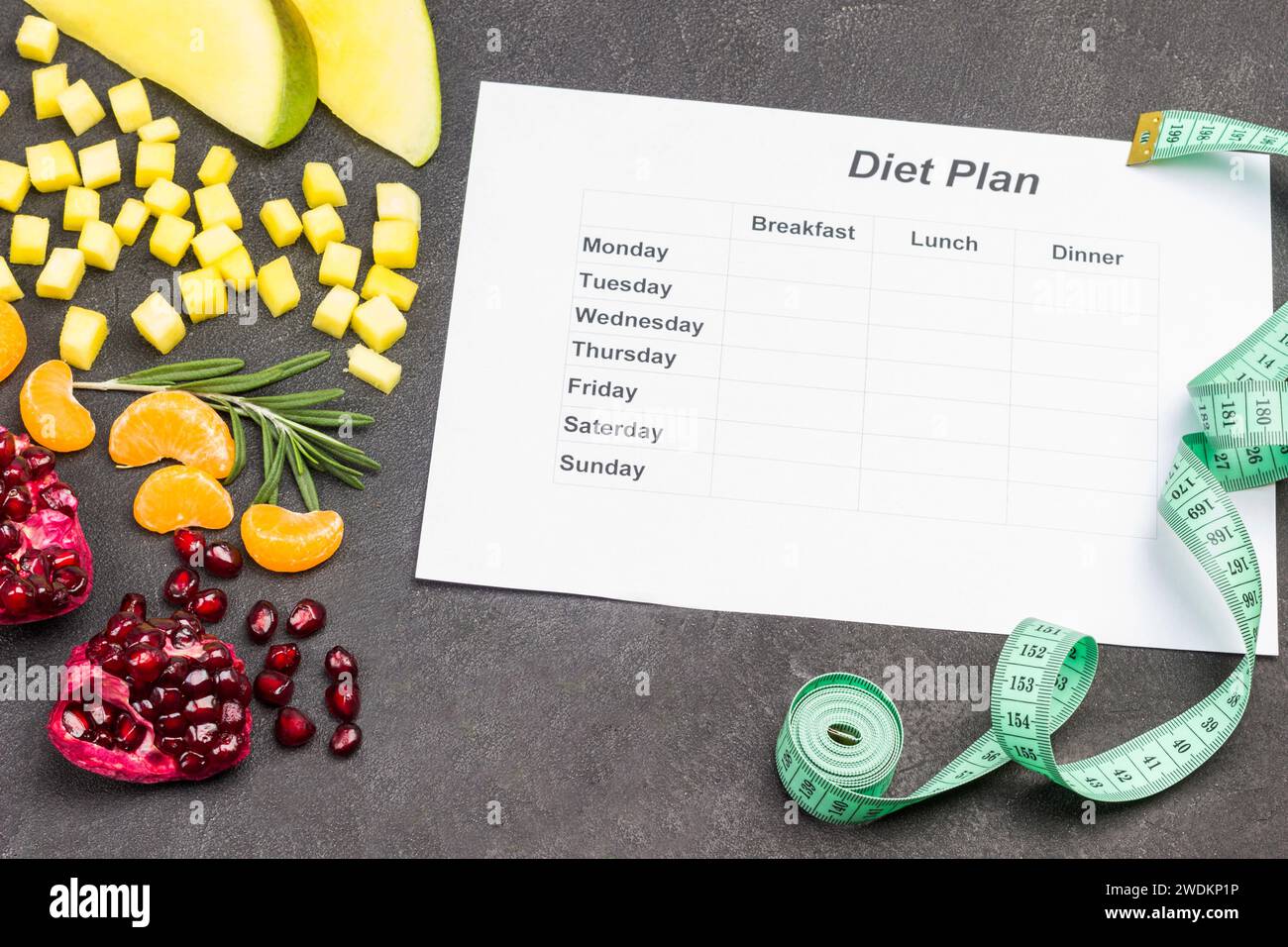 Sheet of paper with diet plan for week. Measuring tape on table. Mango ...