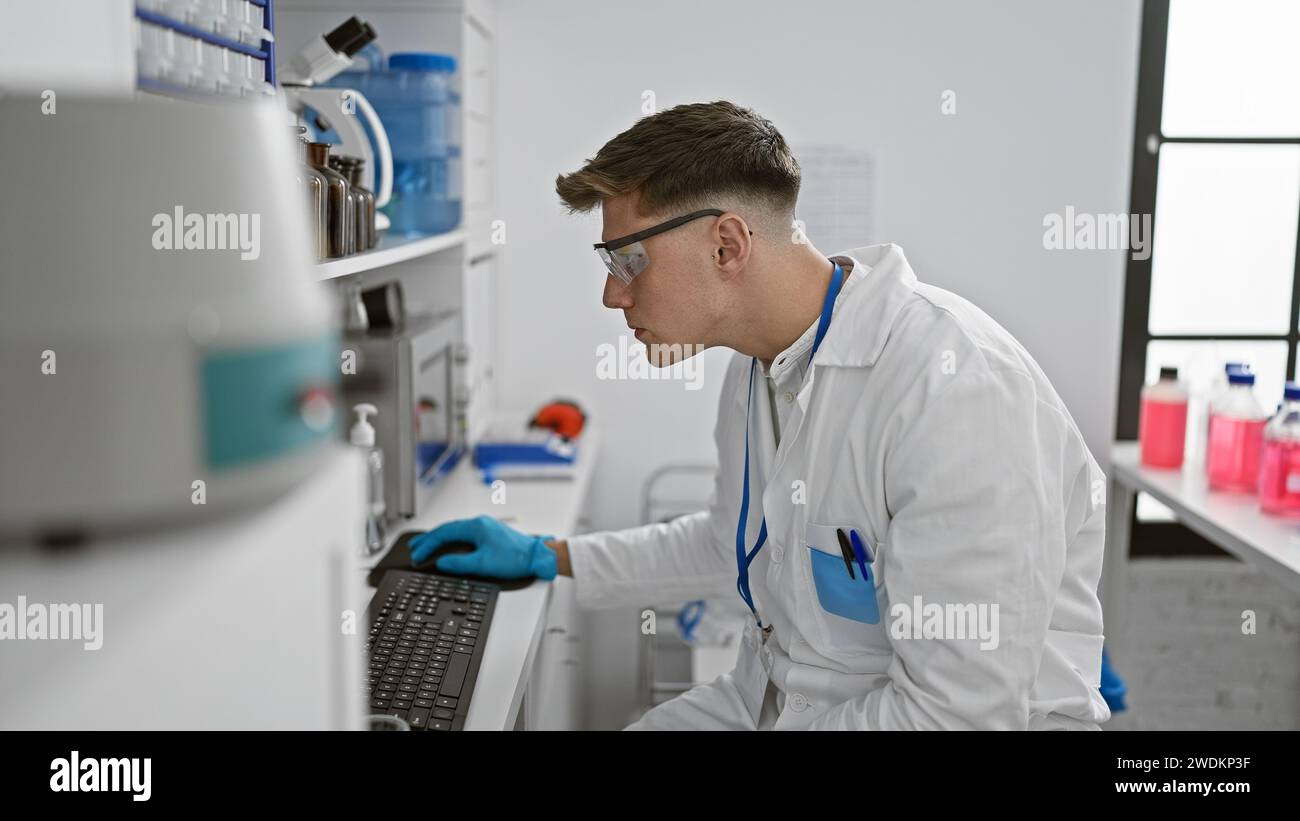 Attractive young caucasian male scientist totally engrossed in typing ...