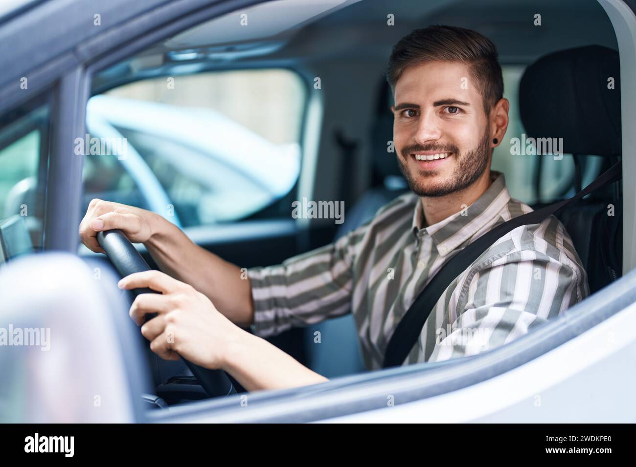 Hispanic man with beard driving car looking positive and happy standing ...