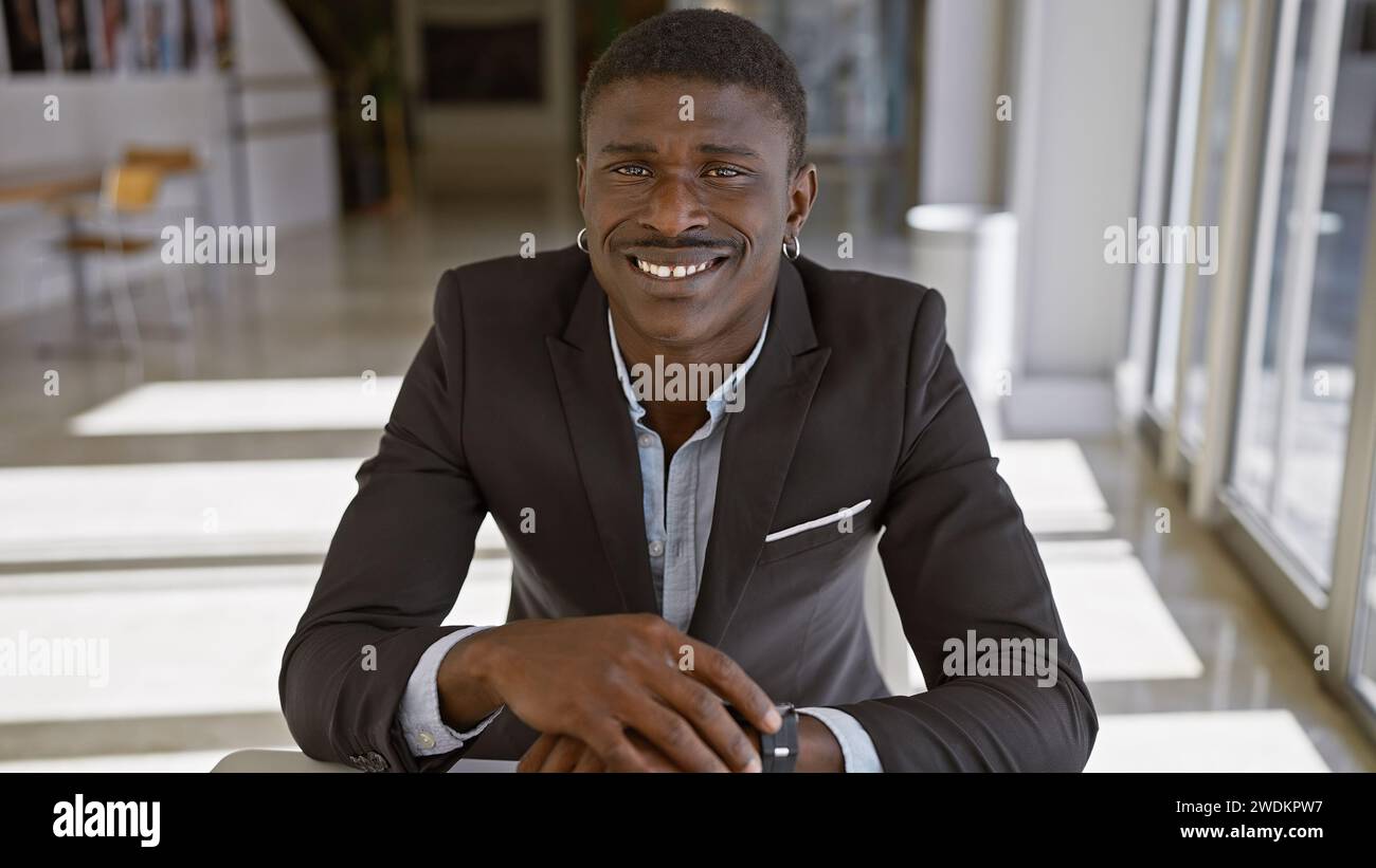 Handsome black man smiling confidently in a bright office interior with ...