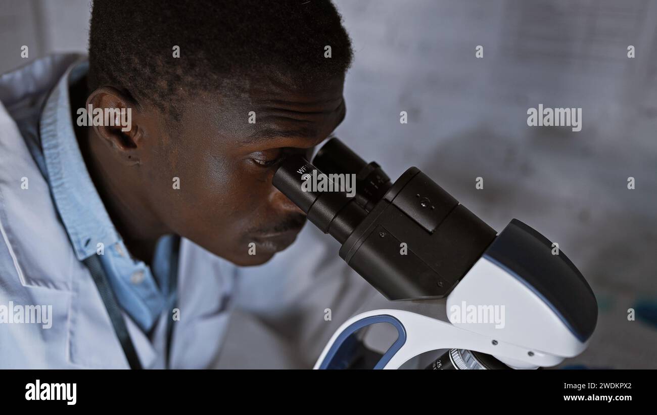African man using microscope in laboratory setting, portraying science ...