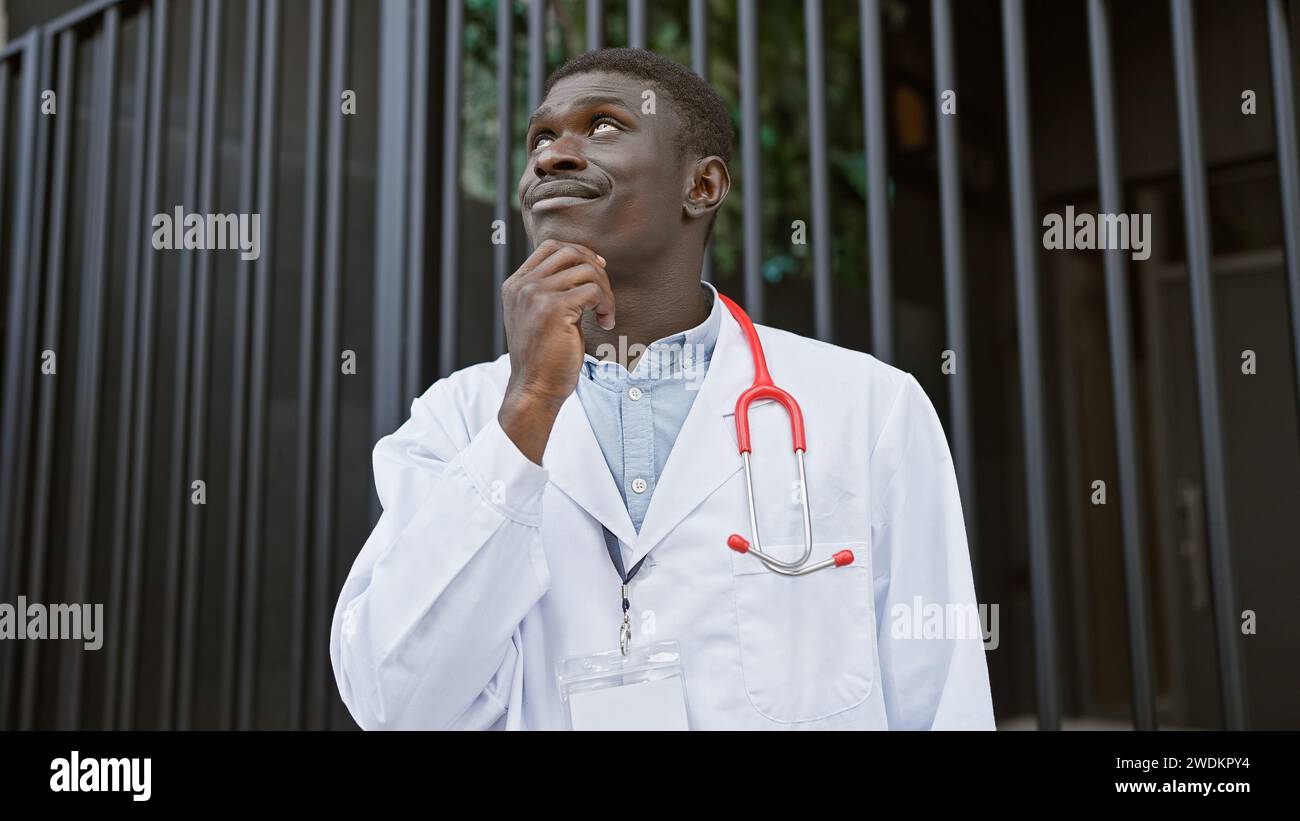 A thoughtful african man in a white lab coat with a stethoscope ...