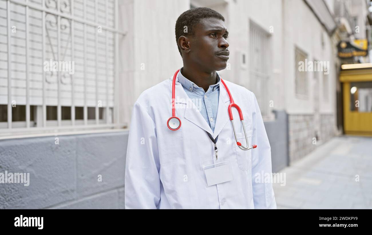 African american male doctor standing thoughtfully in an urban street ...