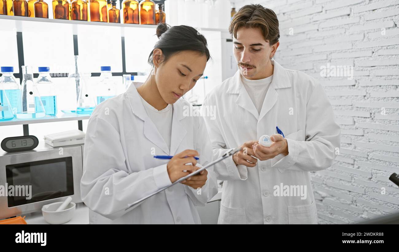 A woman and man in white lab coats examine a sample in a modern ...