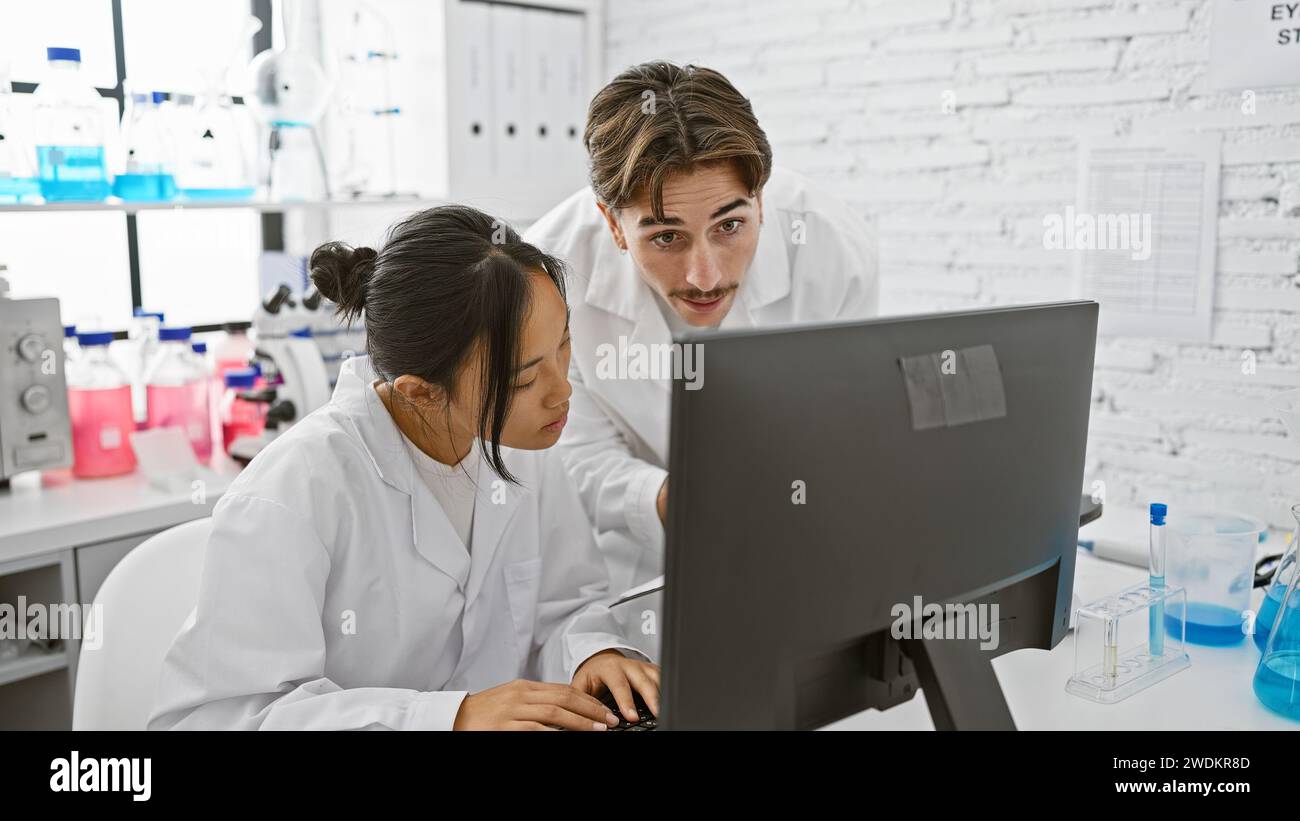 A man and woman work together in a laboratory, looking intently at a ...