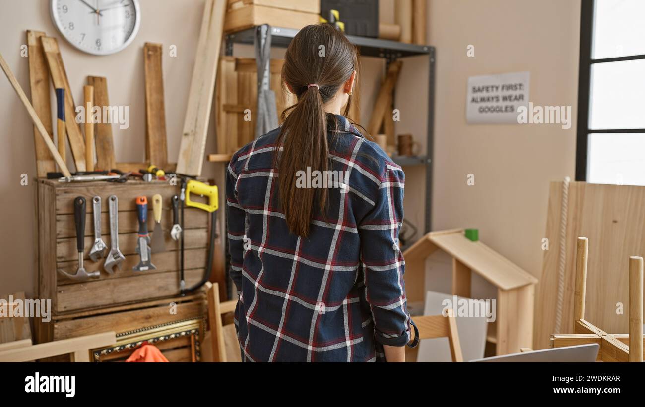 Hispanic woman carpenter in workshop surrounded by tools and wood ...