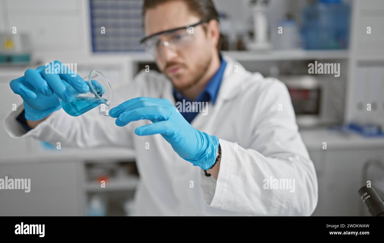 Young hispanic man scientist pouring liquid on sample at laboratory ...