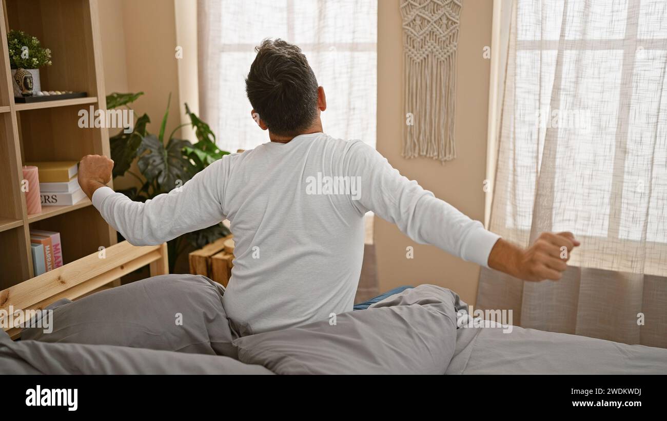 Handsome young hispanic man with grey hair stretching his arms, waking ...