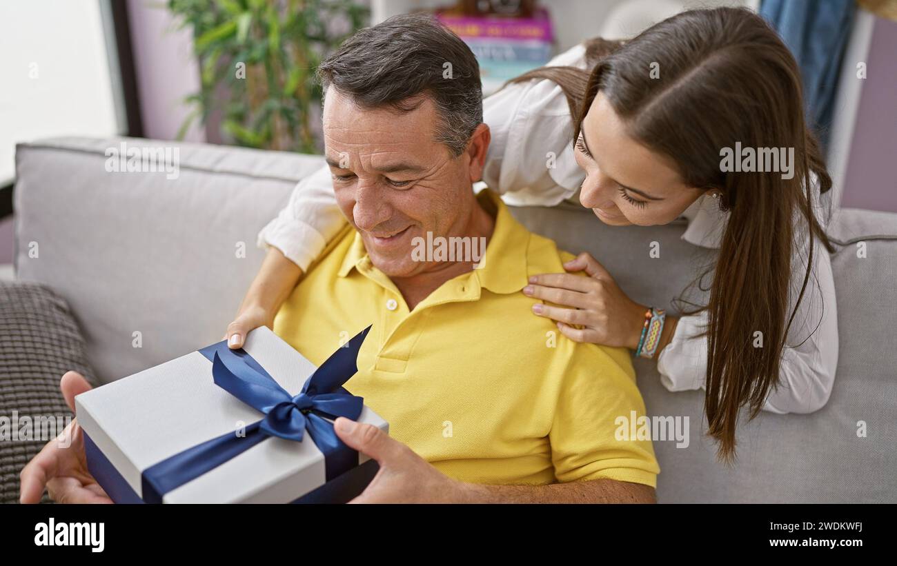 At home, a surprised father and daughter smiling together, sitting on ...