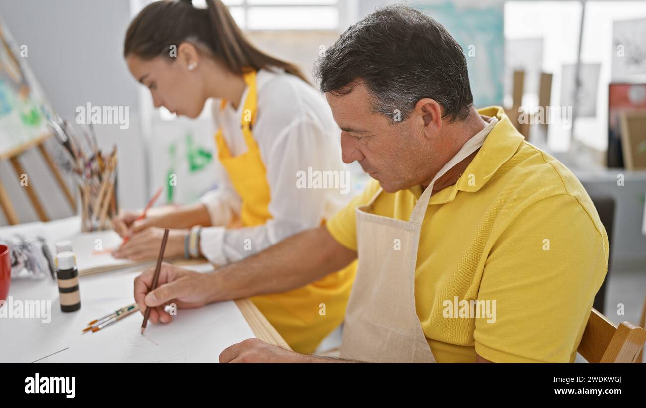 Man and woman artists, deep in concentration, sitting together in art ...