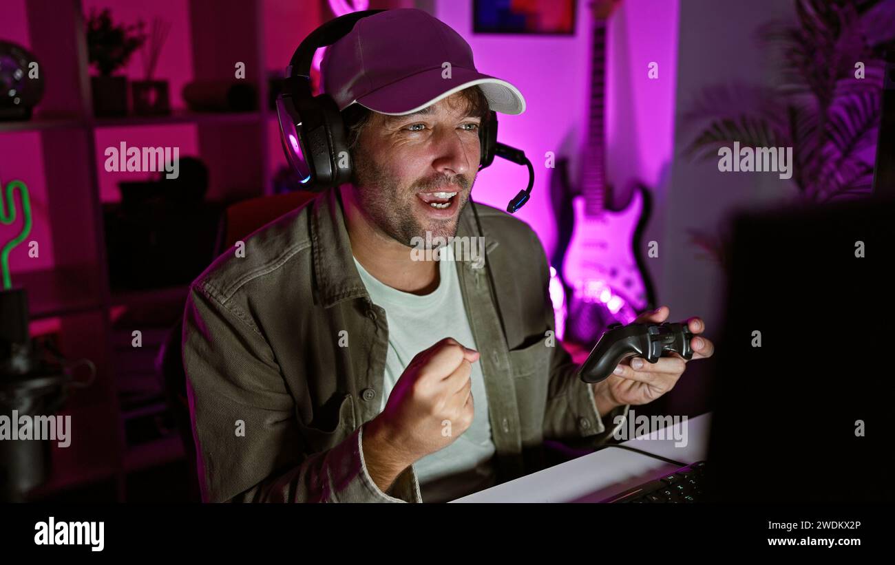 Excited caucasian man gaming at night in a dark room with neon lights ...